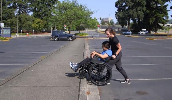 woman pushing wheelchair over curb